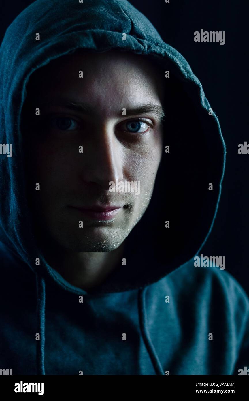 Portrait of a young blue-eyed man with a hood covering his head who in ...