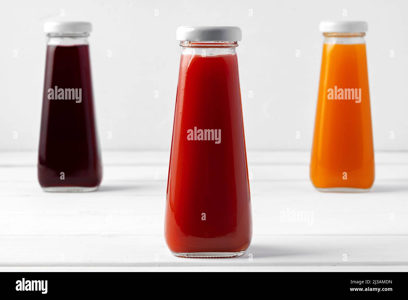 Glass bottles of different juices on white background Stock Photo - Alamy