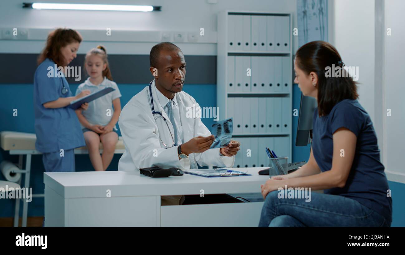 Physician explaining radiography diagnosis to mother in office at ...