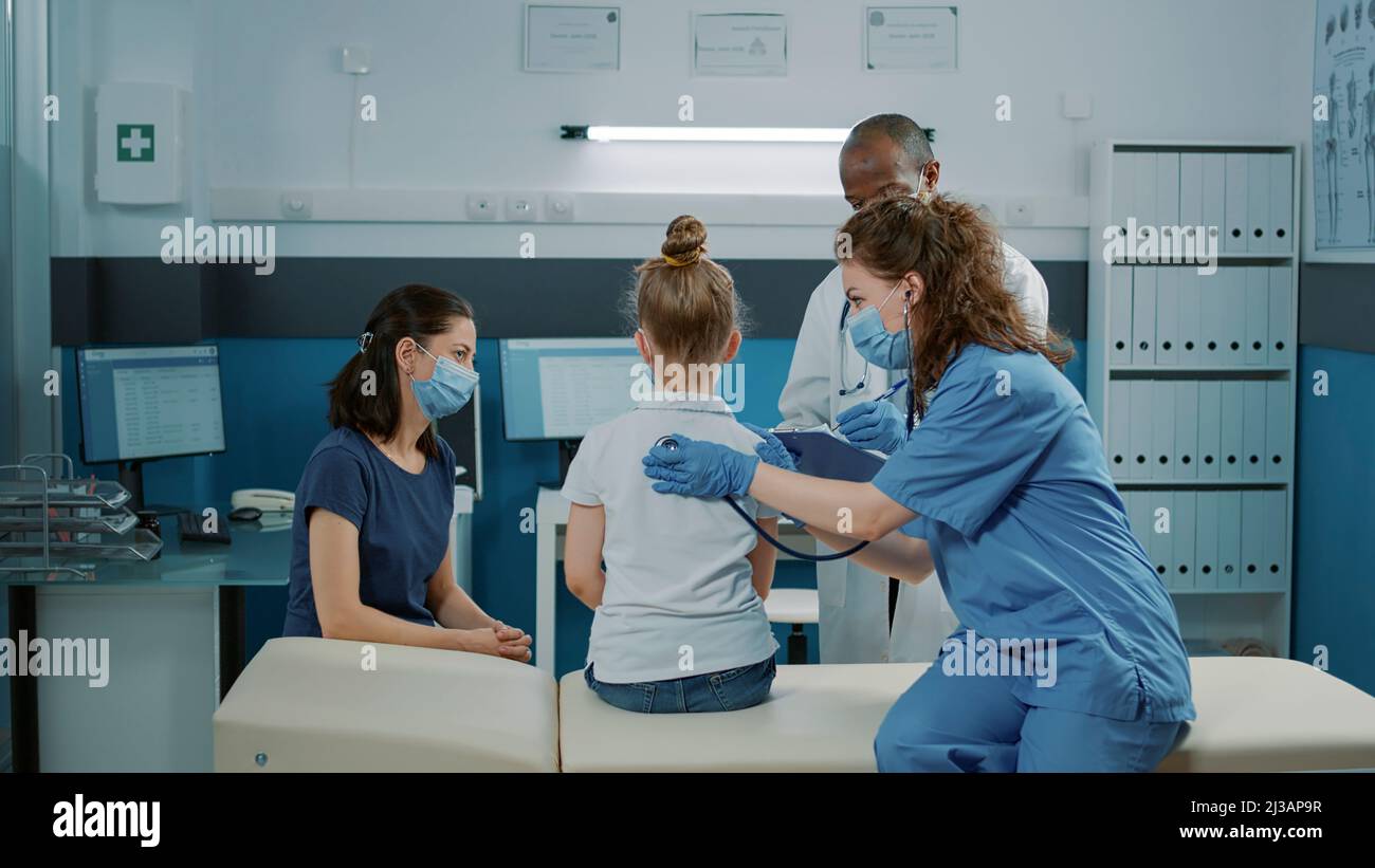 Woman nurse using stethoscope on small kid to do pulse exam in office ...