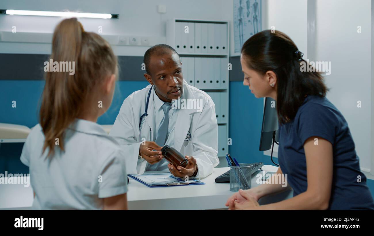 Pediatrician giving bottle of pills to parent of small kid with illness ...