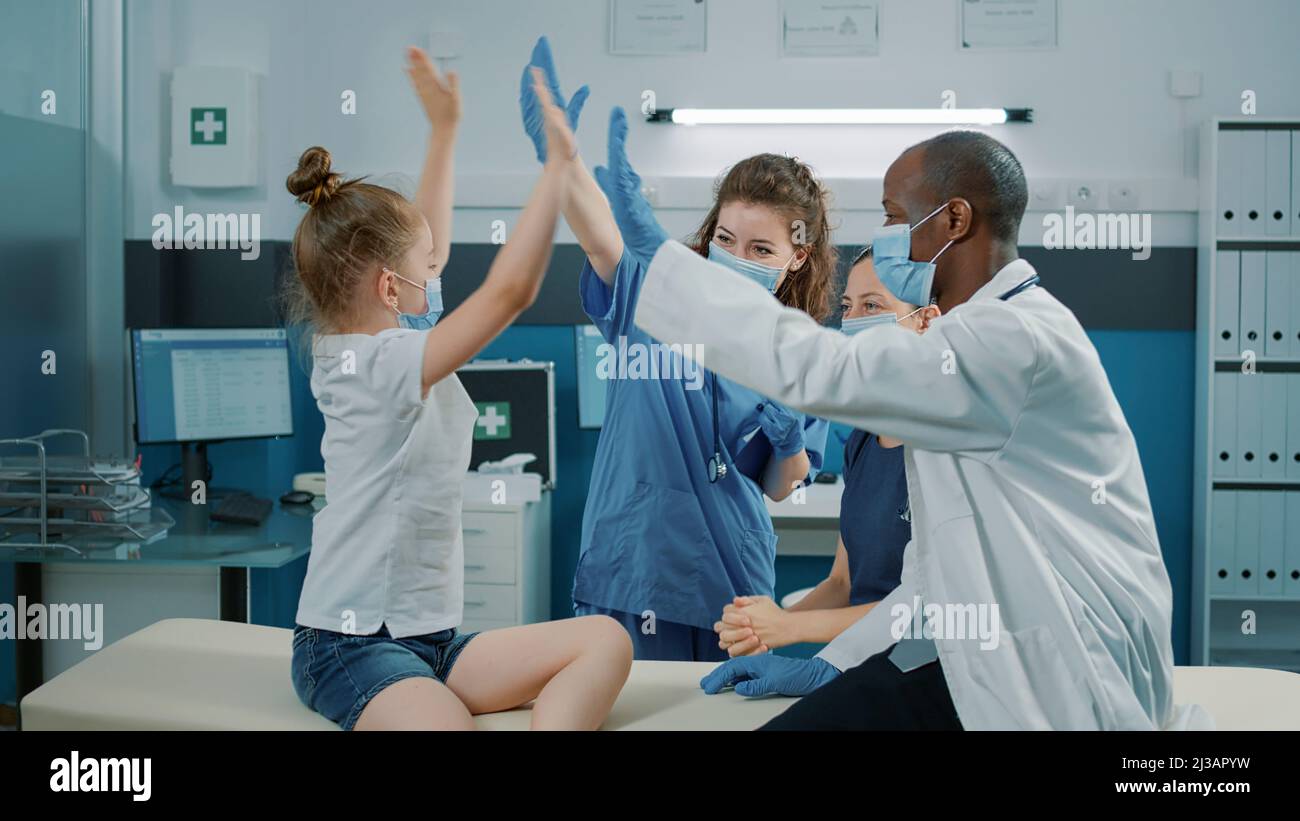 Cheerful nurse and medic giving highfive to small child after ...