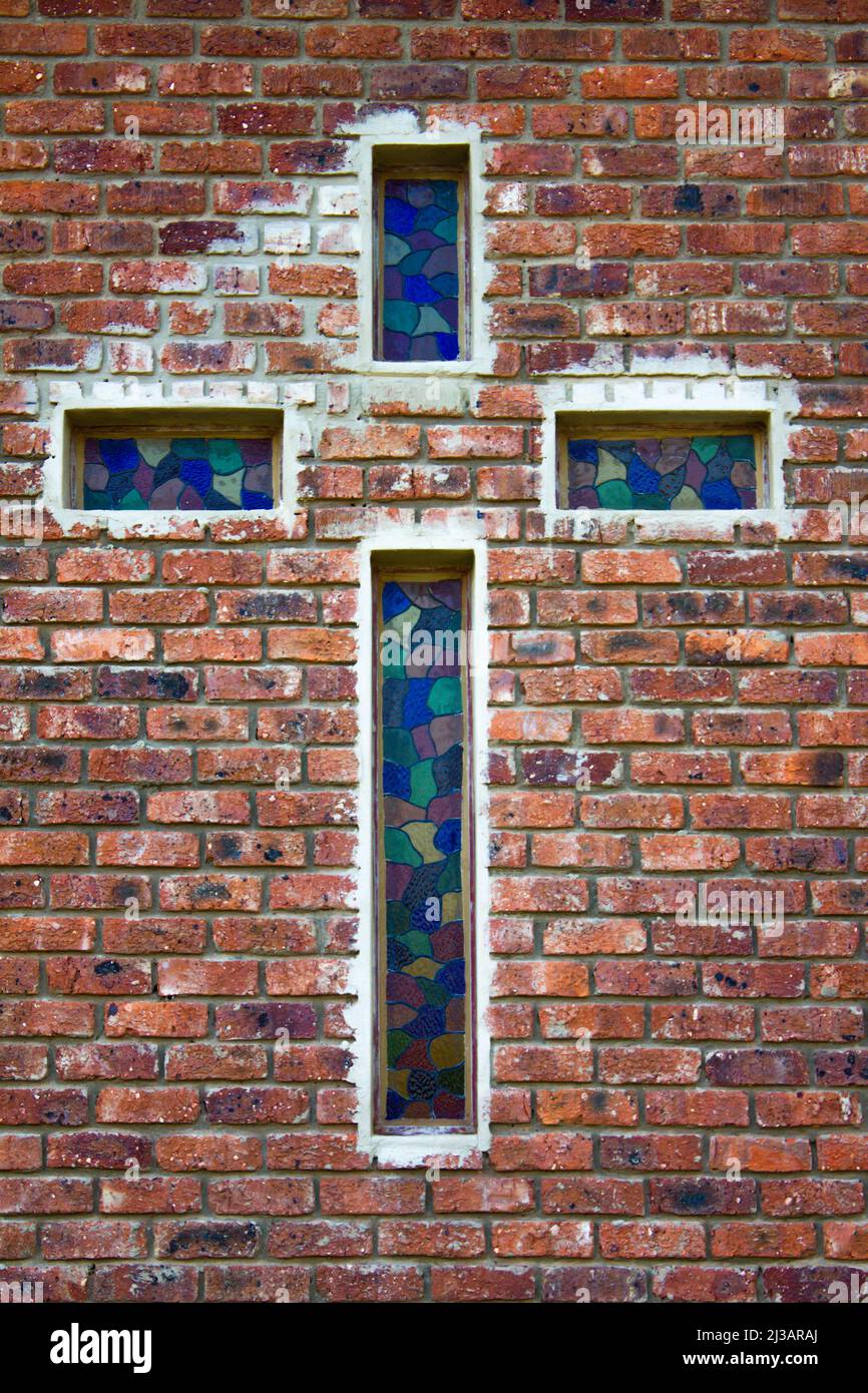 A vertical shot of a cross- shaped window of a church with bricks Stock ...