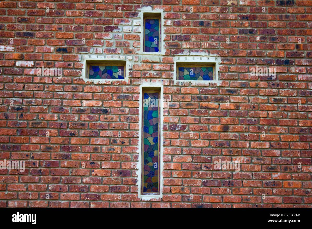 A closeup shot of a cross- shaped window of a church with bricks Stock ...