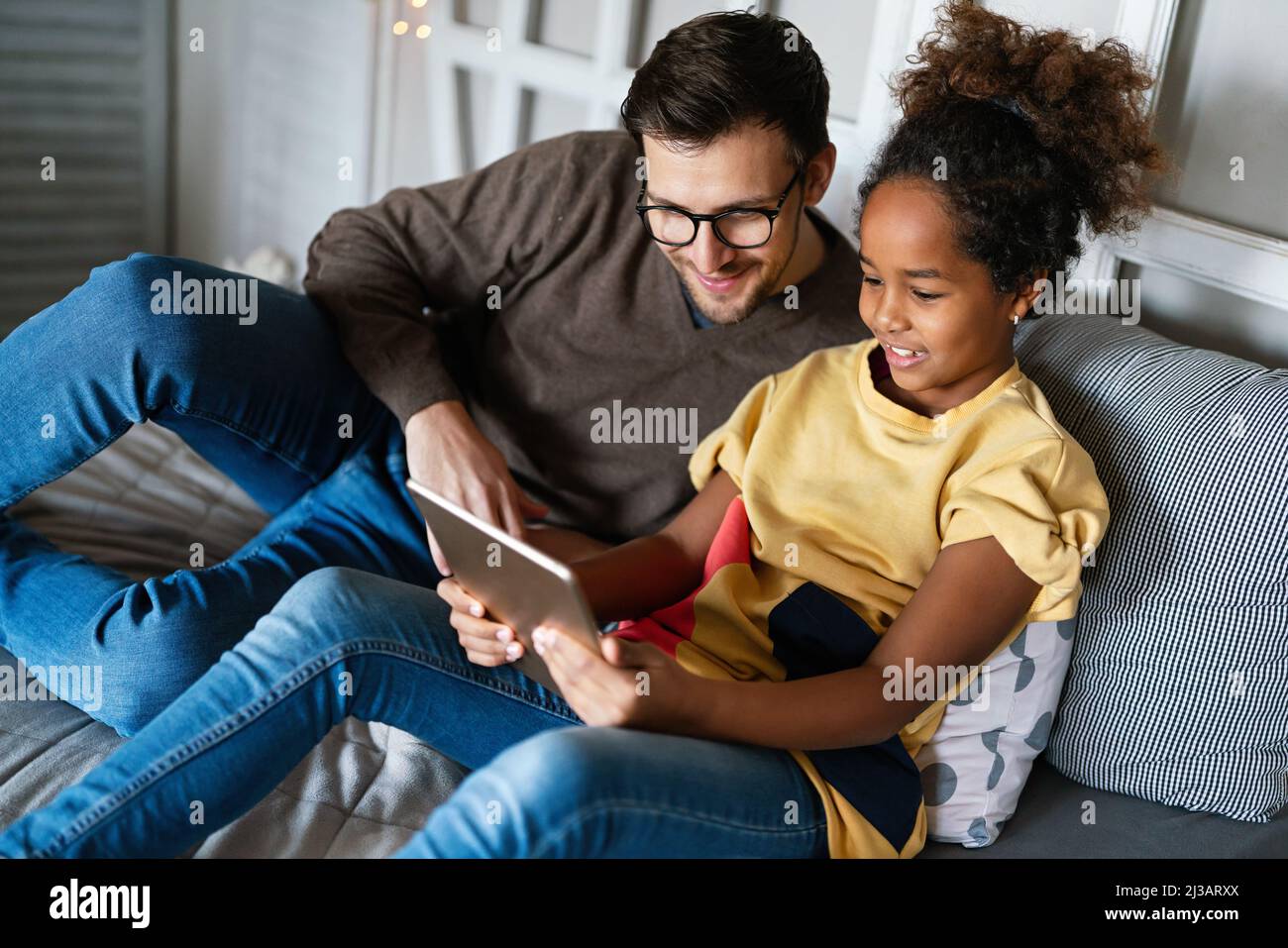 Multiethnic father and child using electronic tablet at home ...