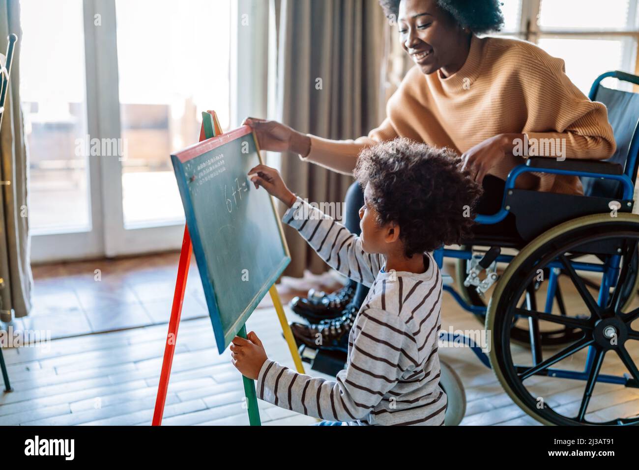 Happy child doing math exercises with her mother ot teacher together ...