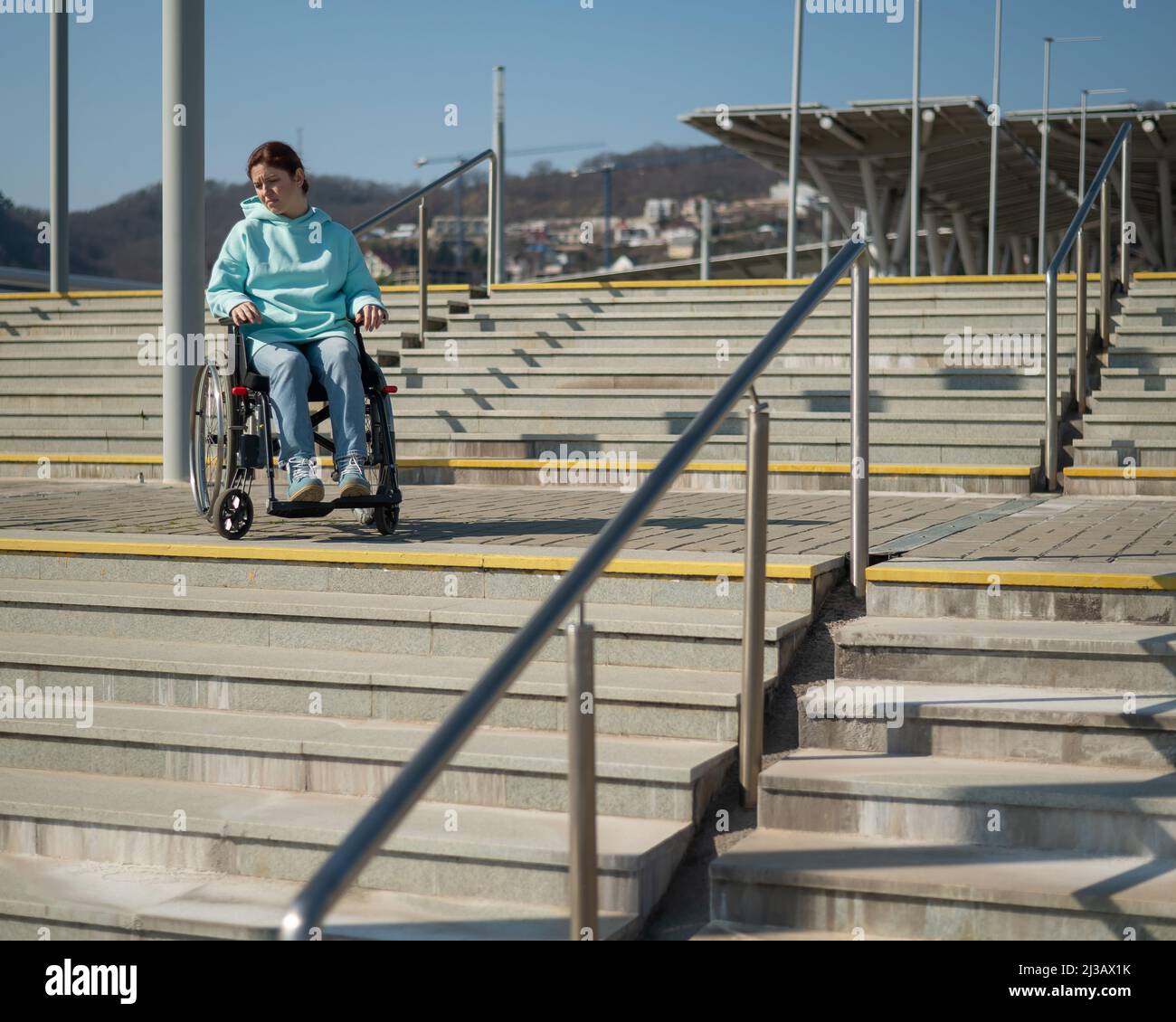 A caucasian woman in a wheelchair cannot go down stairs without a ramp ...