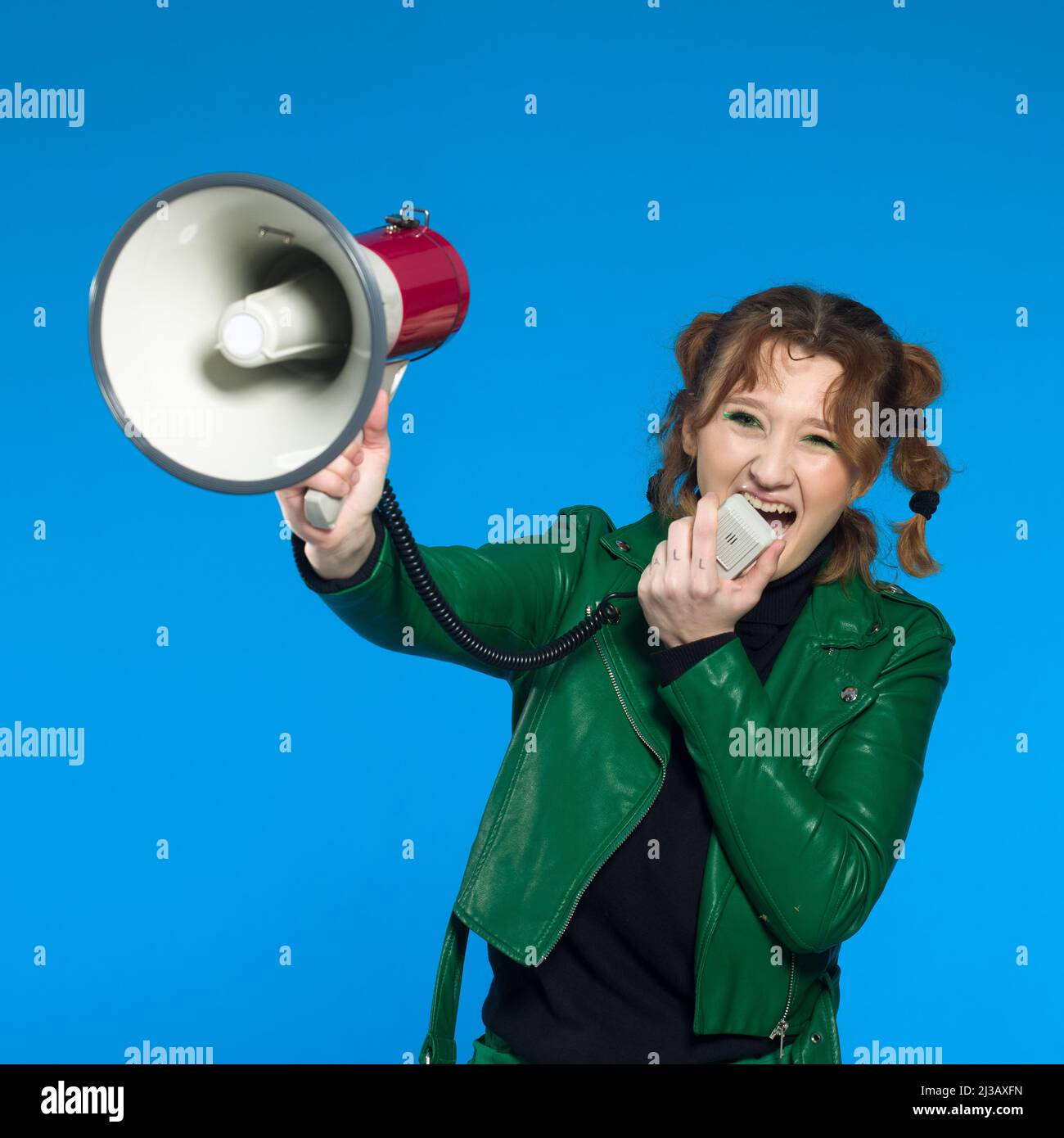 Funny young female shouting through megaphone. Young woman using ...