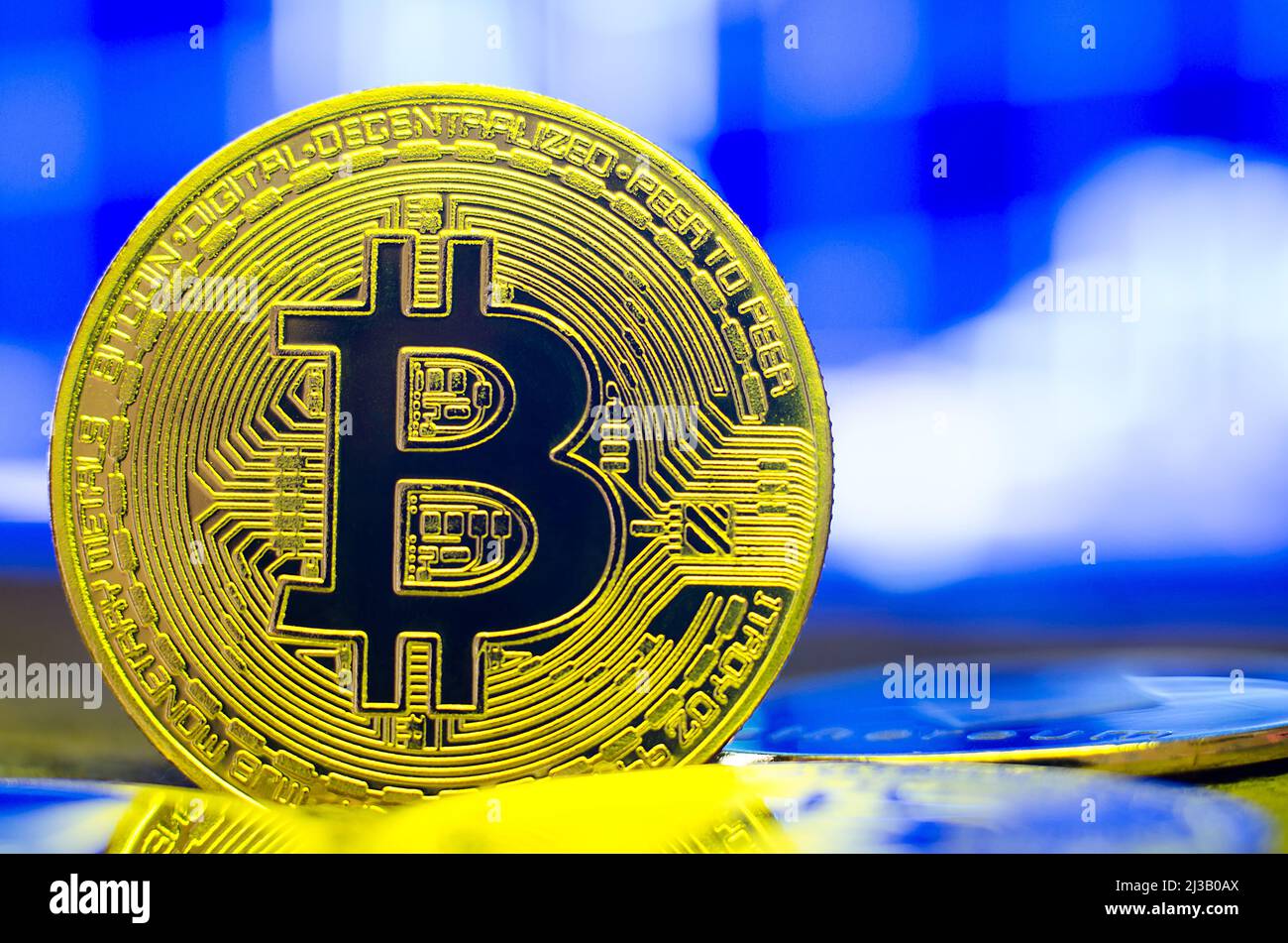 Yellow bitcoin coin on the background of a blue blurred chart close-up ...