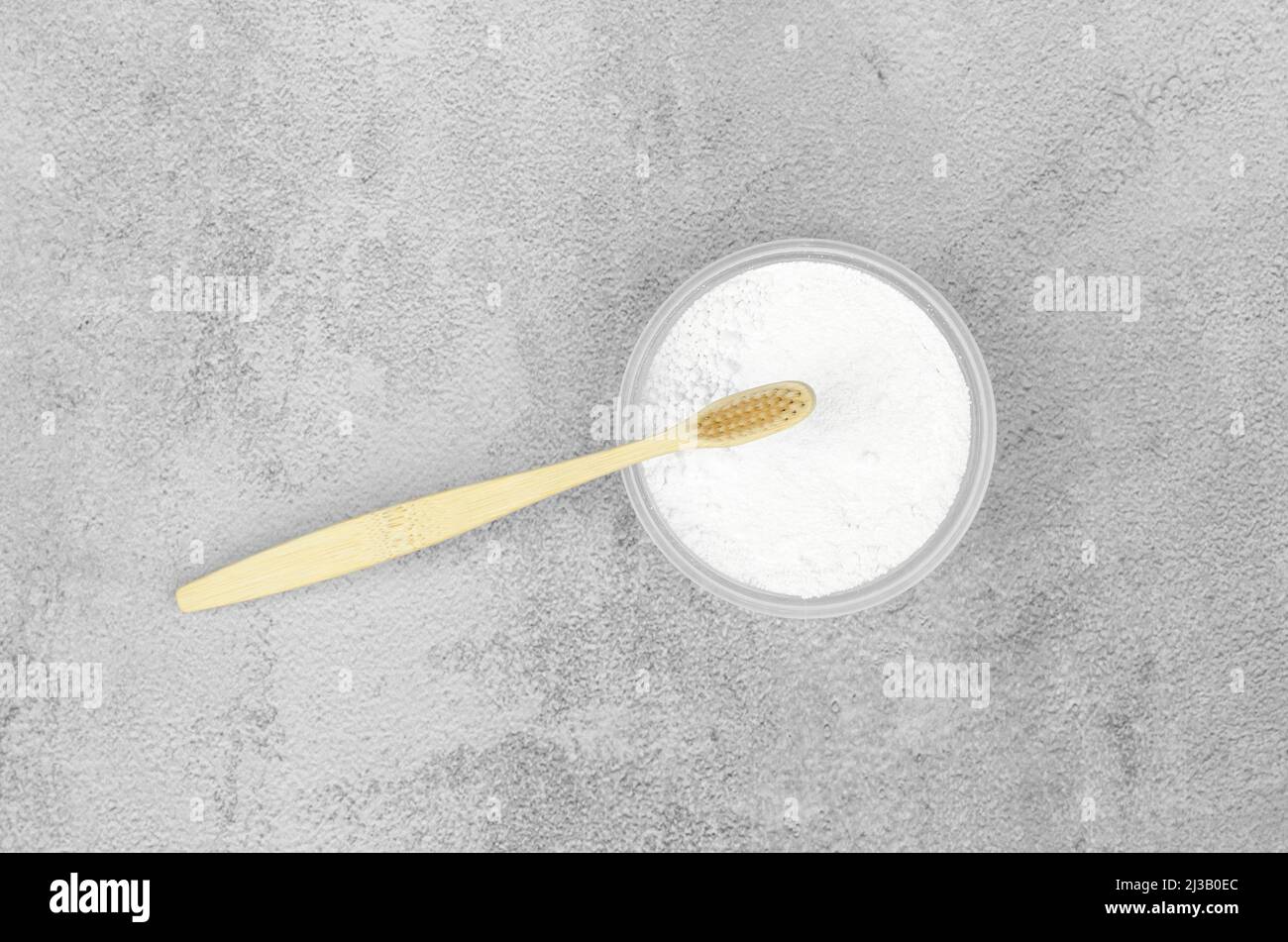 Wooden toothbrush and tooth powder on concrete background, top view ...