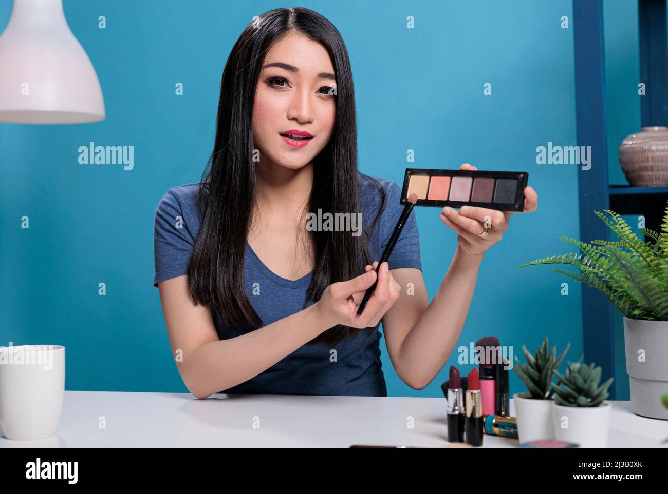 Social media influencer holding make up palette showing at camera while ...