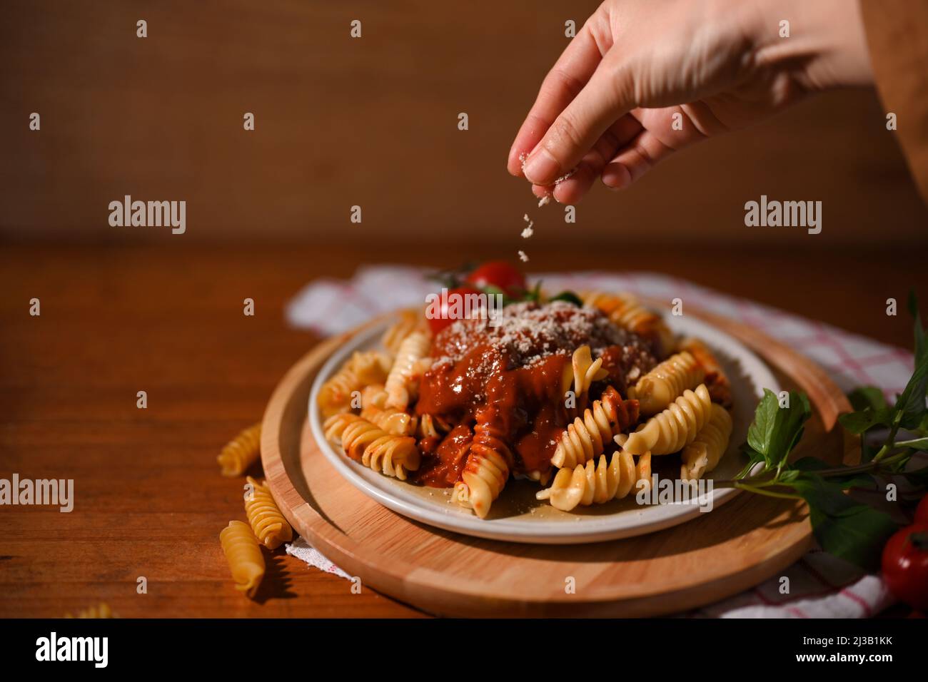 Close-up image, Female chef hands sprinkling Fusilli pasta with ...