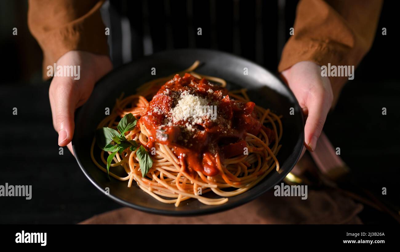 Top view, Female hands holding or serving a plate of Italian spaghetti ...