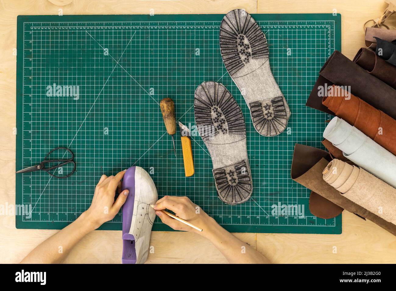 Craftsman drawing shoe last pattern creating leatherwork at studio ...