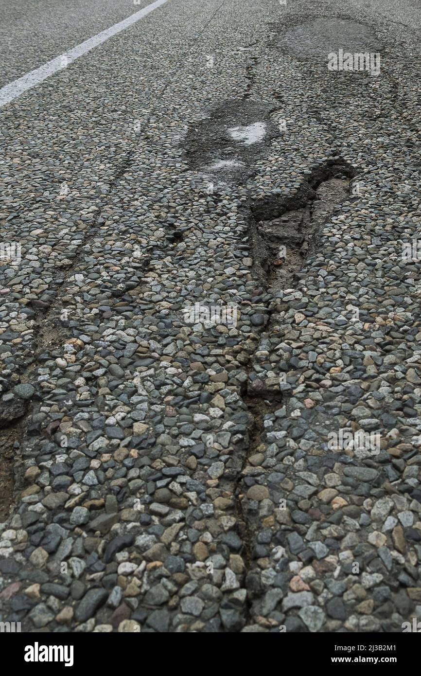 Pits and cracks in the asphalt road. Ruined roadbed. Poor condition of ...