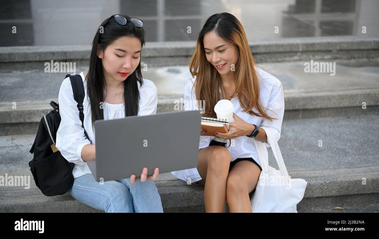 Attractive Asian woman discussing her ideas with a classmate while ...