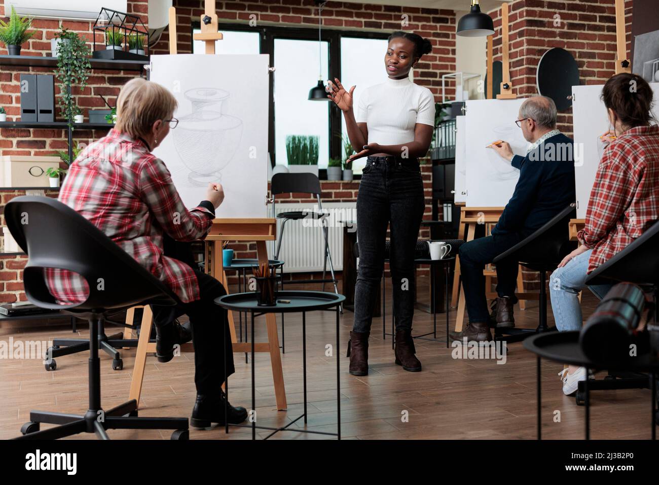 African american teacher giving advice to students explaining sketching ...