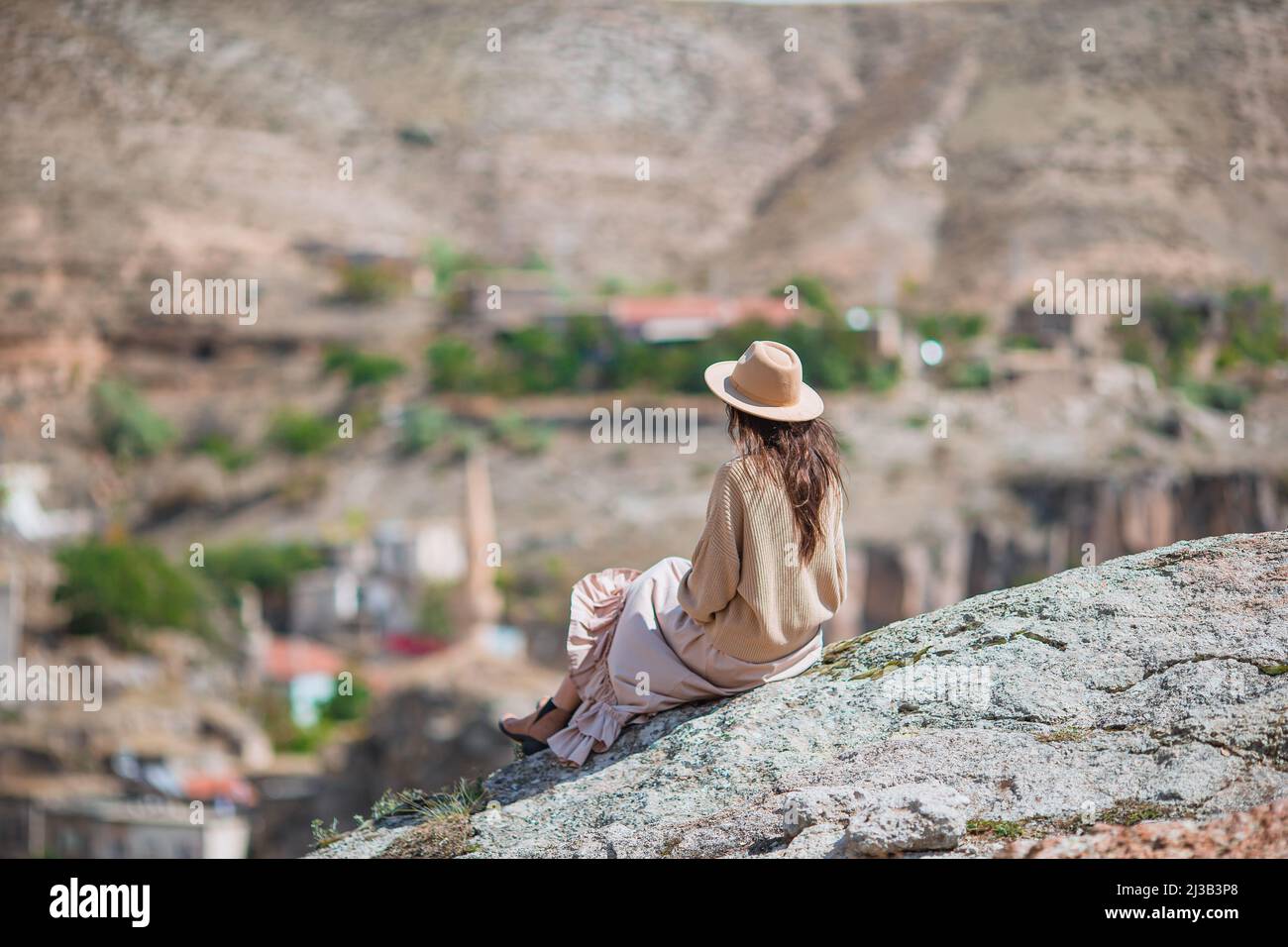 Young woman on background of ancient cave formations in Cappadocia ...