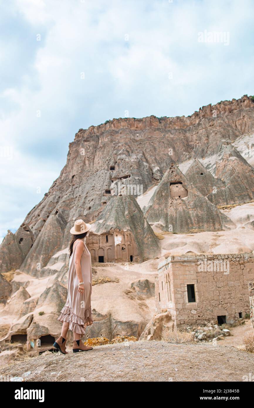 Young woman on background of ancient cave formations in Cappadocia ...