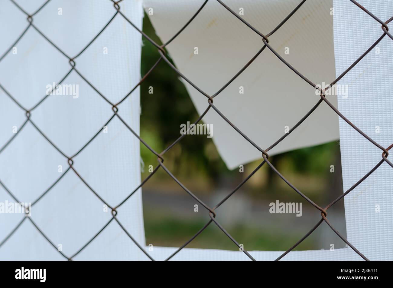The banner is attached to Chain-link fencing. White banner with ...