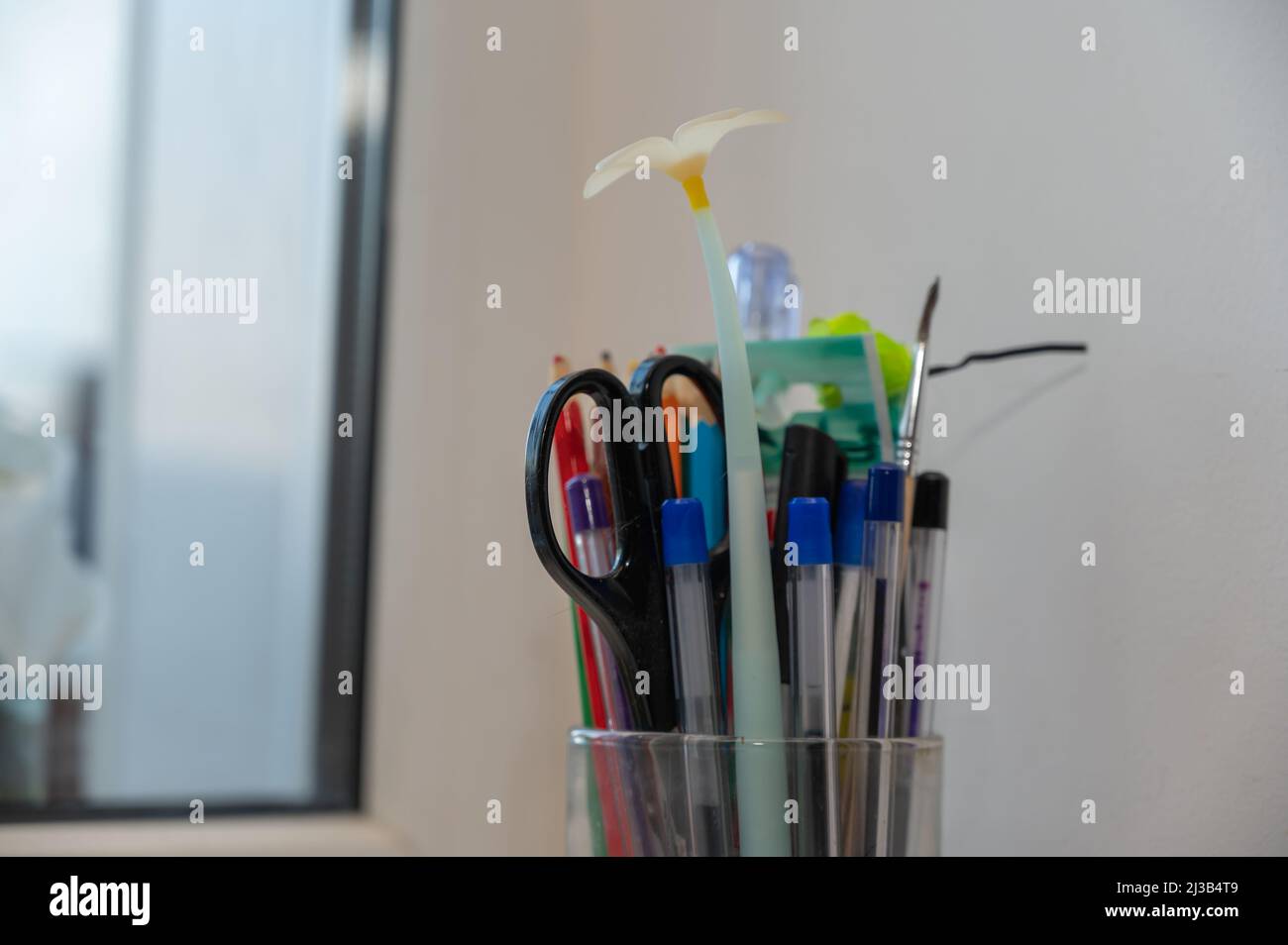 Pencils, pens, brushes for drawing in a glass beaker. Office or school ...