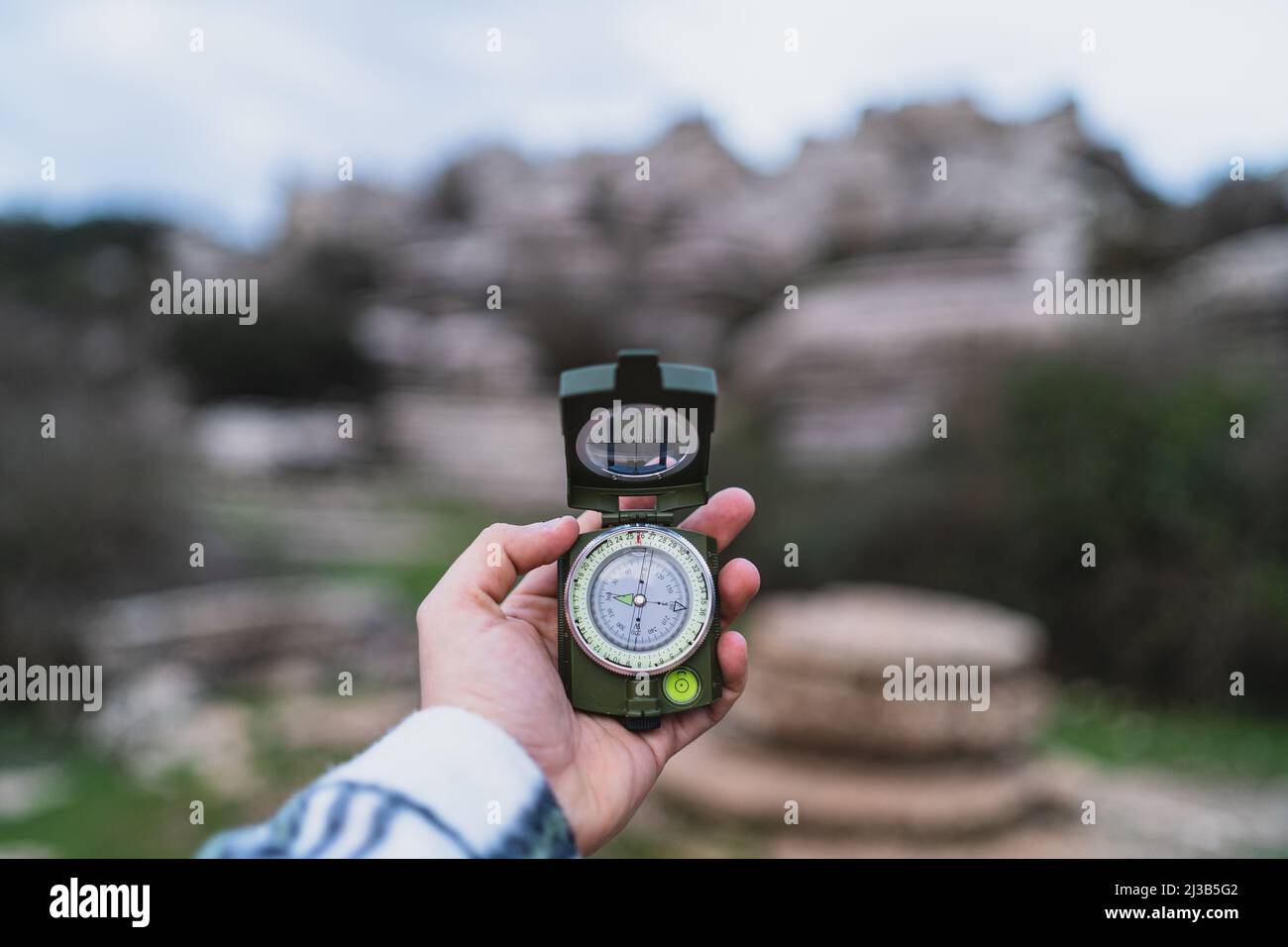 An adult hand holding an open green tactical prismatic compass during ...