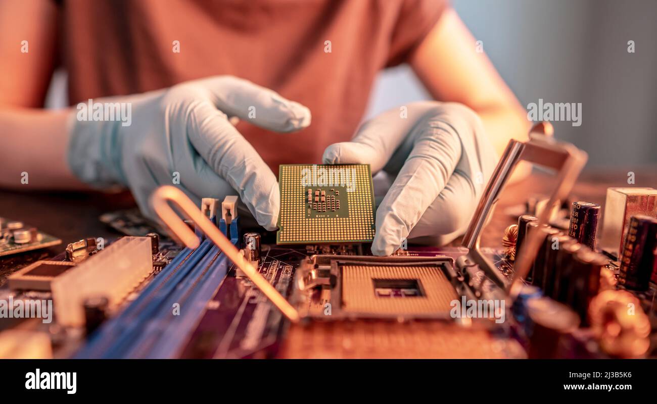 The engineer's gloved hand is holding the CPU chip against the ...