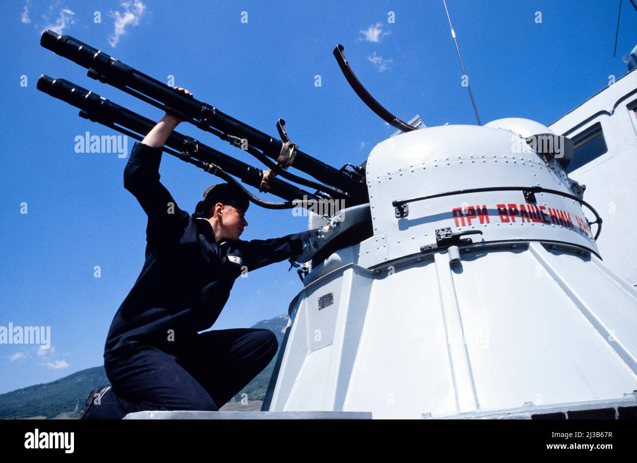 A KGB young naval rating cleans the turret gun on a border parol ship ...