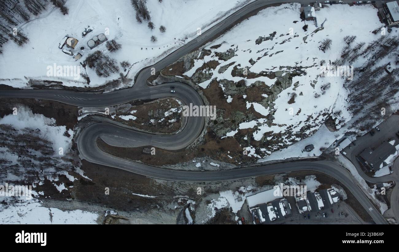 An aerial top view of a curvy road on the snowy mountains Stock Photo ...