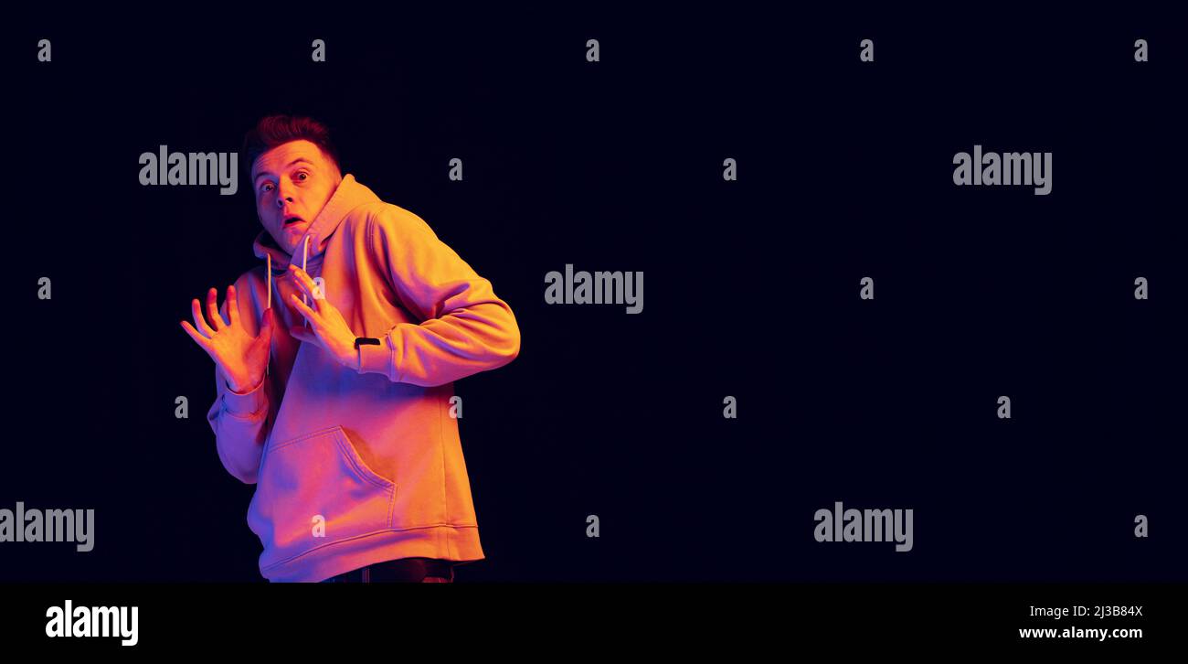 Flyer with young scared man wearing hoodie isolated over dark studio ...