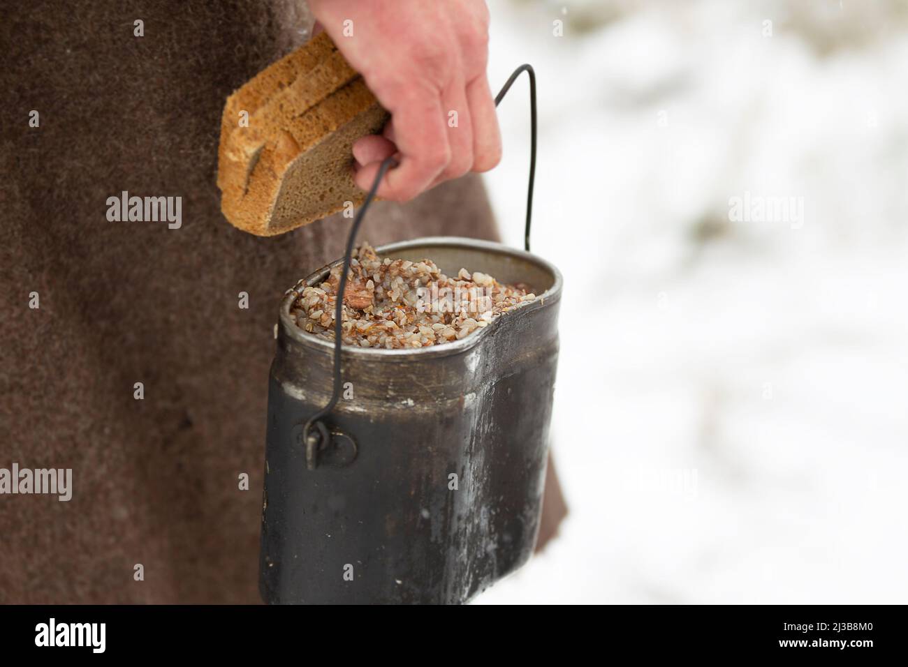 The soldier's hand holds a military cauldron with buckwheat porridge ...