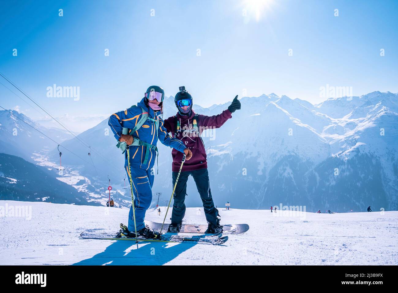 Snowboarder and skier standing against beautiful mountains at winter ...