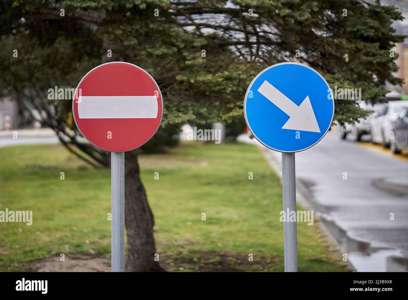 Two street signs in red and blue with an arrow Stock Photo - Alamy