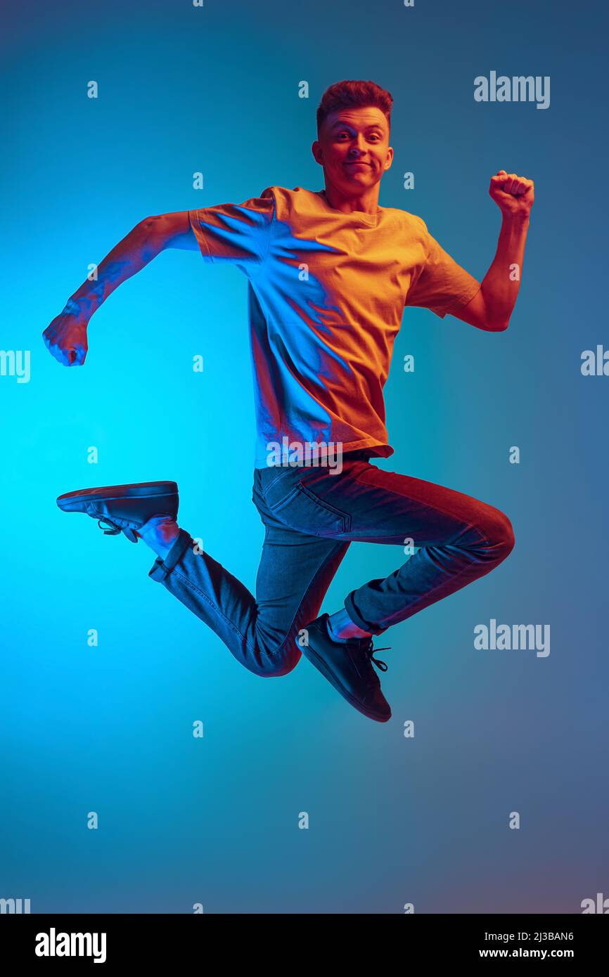 Dynamic portrait of young excited man, student cheerfully jumping in ...