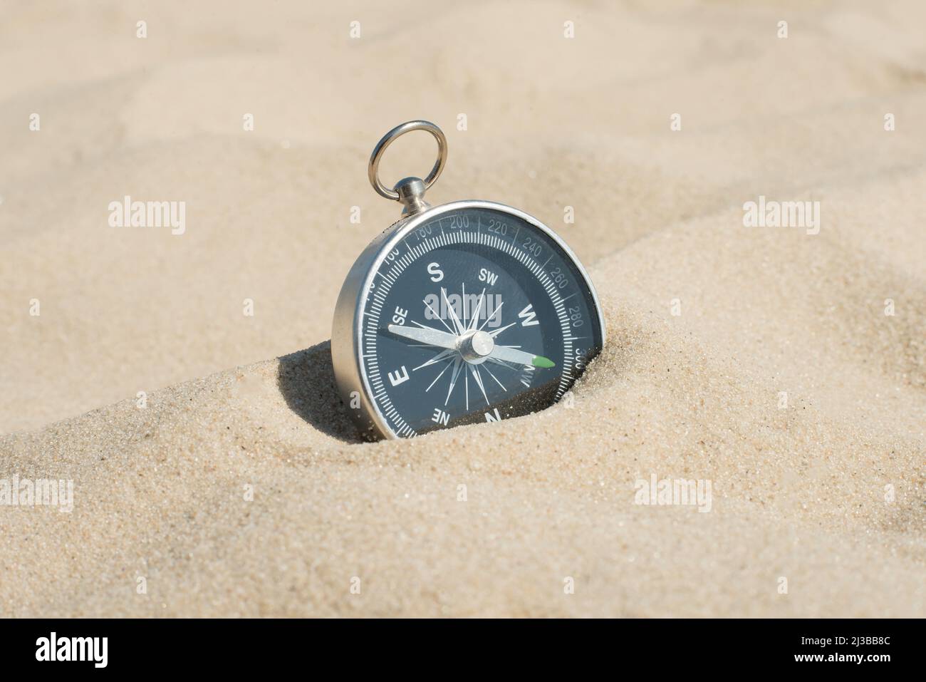 Compass buried in the sand on the beach concept of lost or direction ...