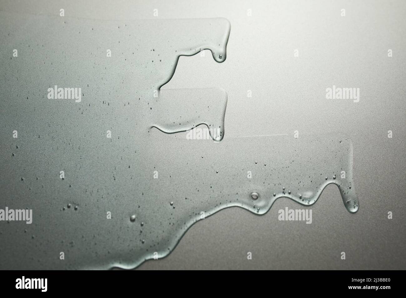 Blue cream liquid gel serum flows down on silver texture, makeup and ...