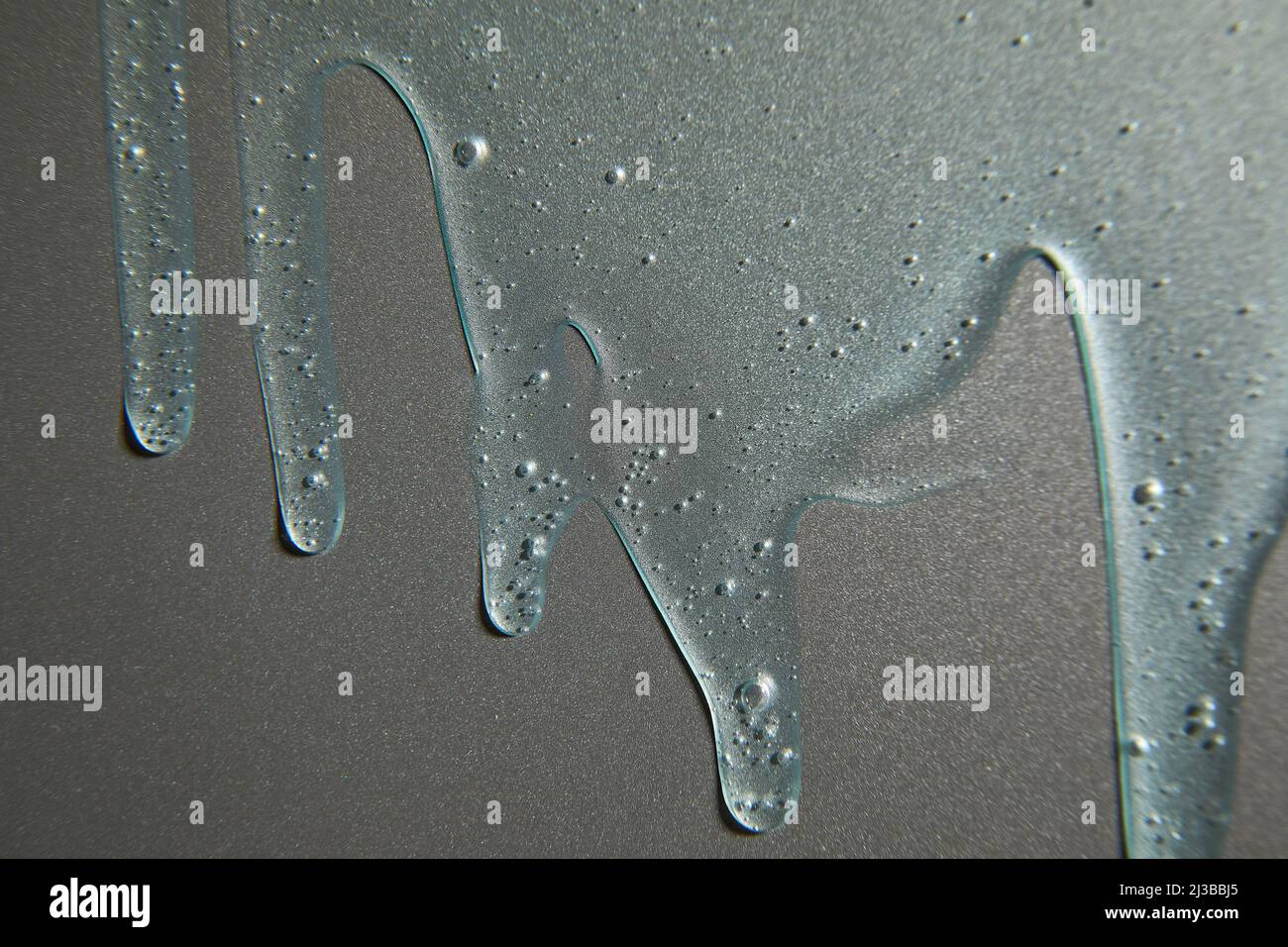 Blue cream liquid gel serum flows down on silver texture, makeup and ...