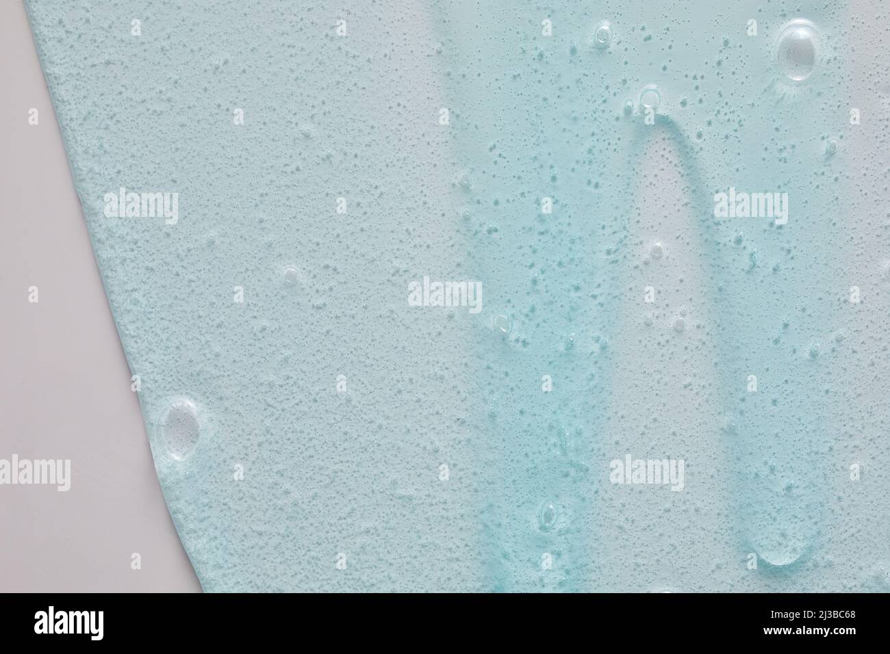 Blue cream liquid gel serum flows down on silver texture, makeup and ...