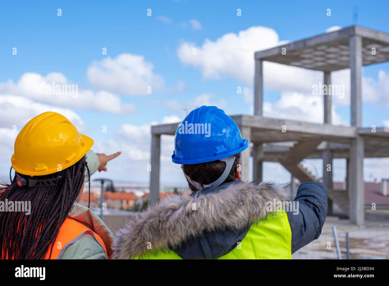 Structural engineer and foreman worker in orange and yellow vests and ...