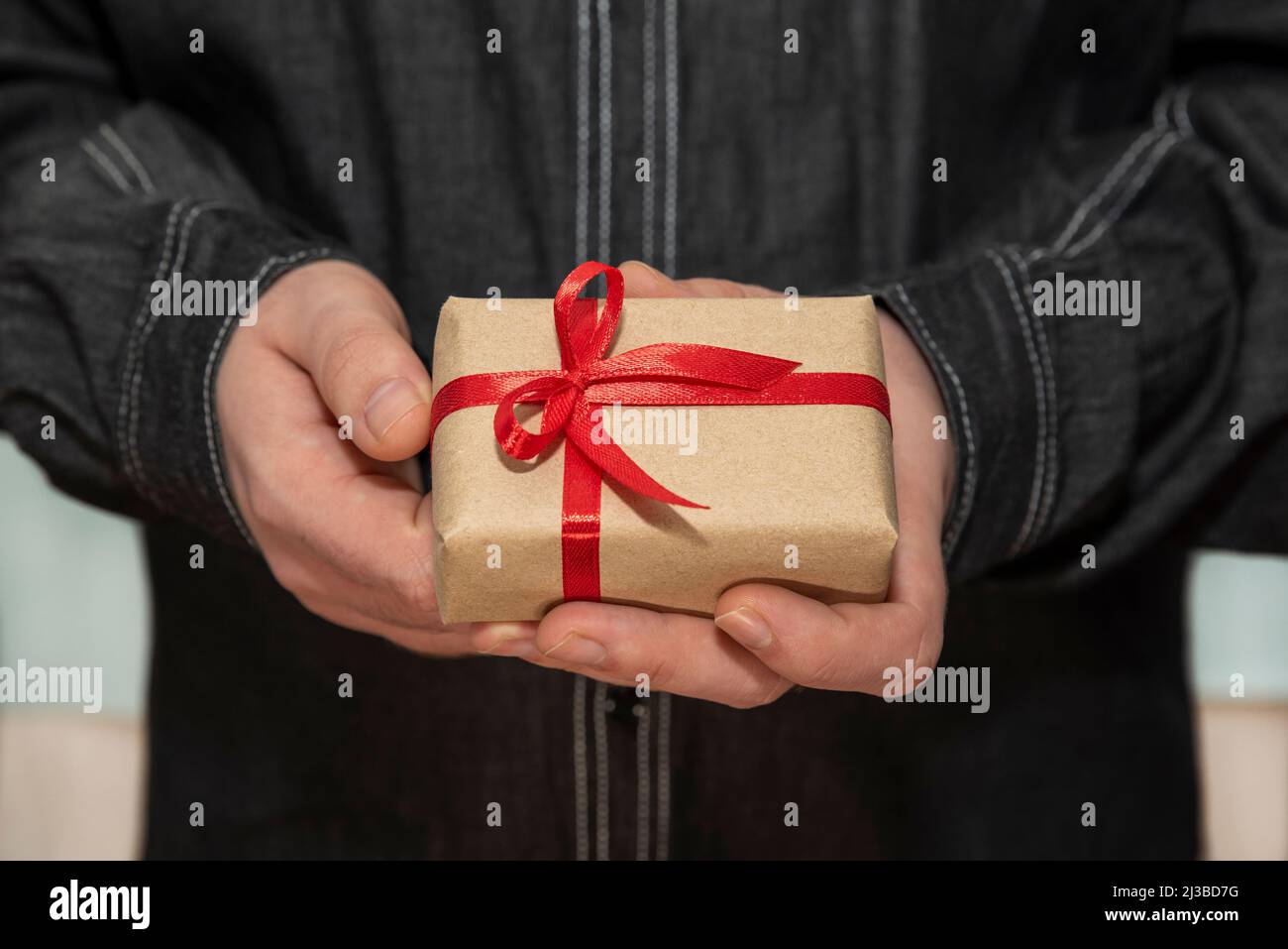 The man is handing a gift box with red ribbon Stock Photo - Alamy