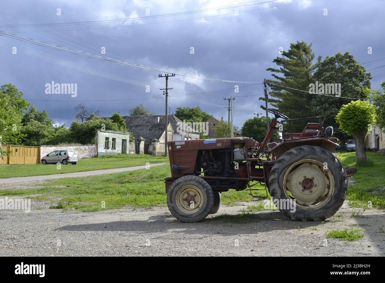 Old type of agricultural tractor with trailer parked in the village ...