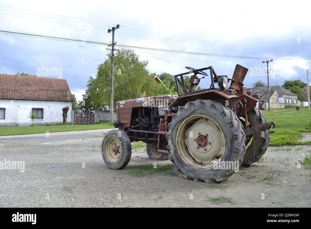 Old type of agricultural tractor with trailer parked in the village ...