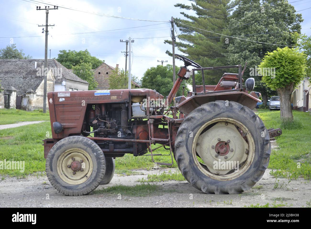 Old type of agricultural tractor with trailer parked in the village ...
