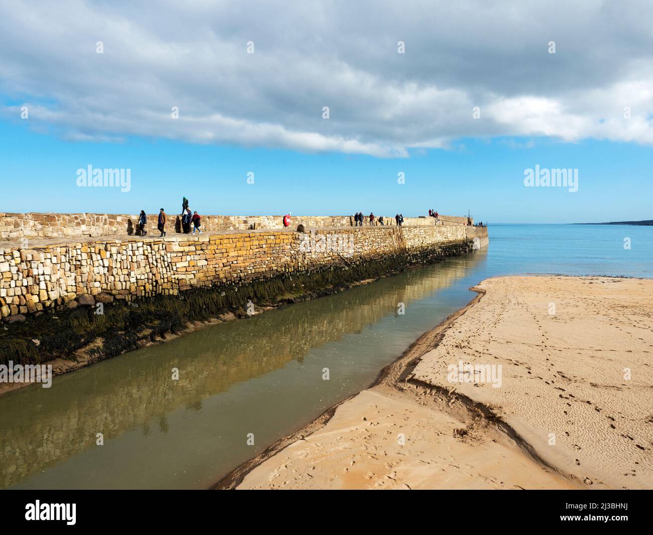 Walking on the sea wall at the harbour in St Andrews Fife Scotland ...