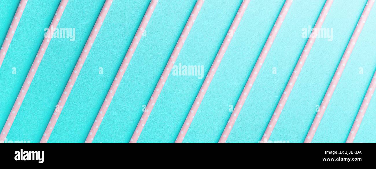 Biodegradable spotted pink paper straw set on blue table background ...