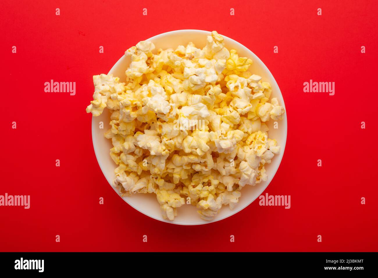 plate with popcorn on a red bright background. movie viewing concept ...