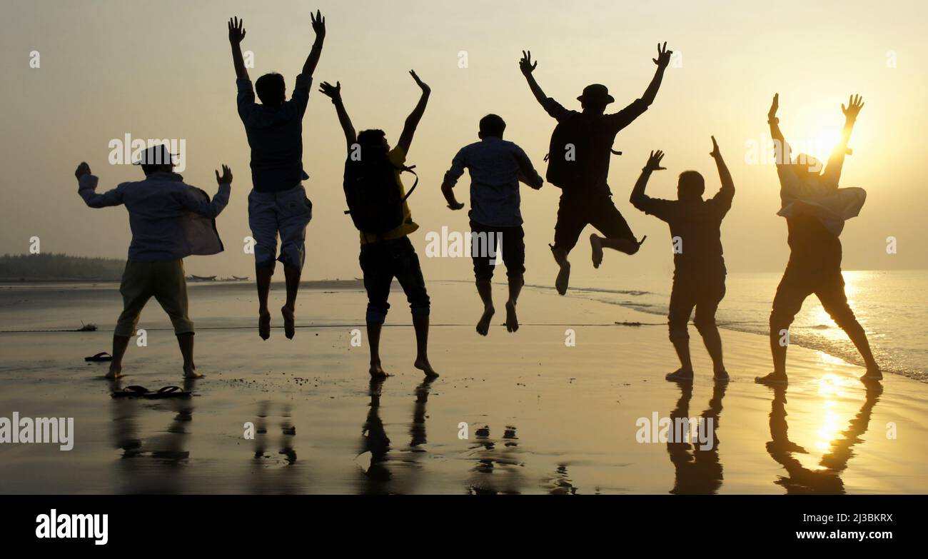 Big group of seven happy friends is having fun and jumping on beach ...