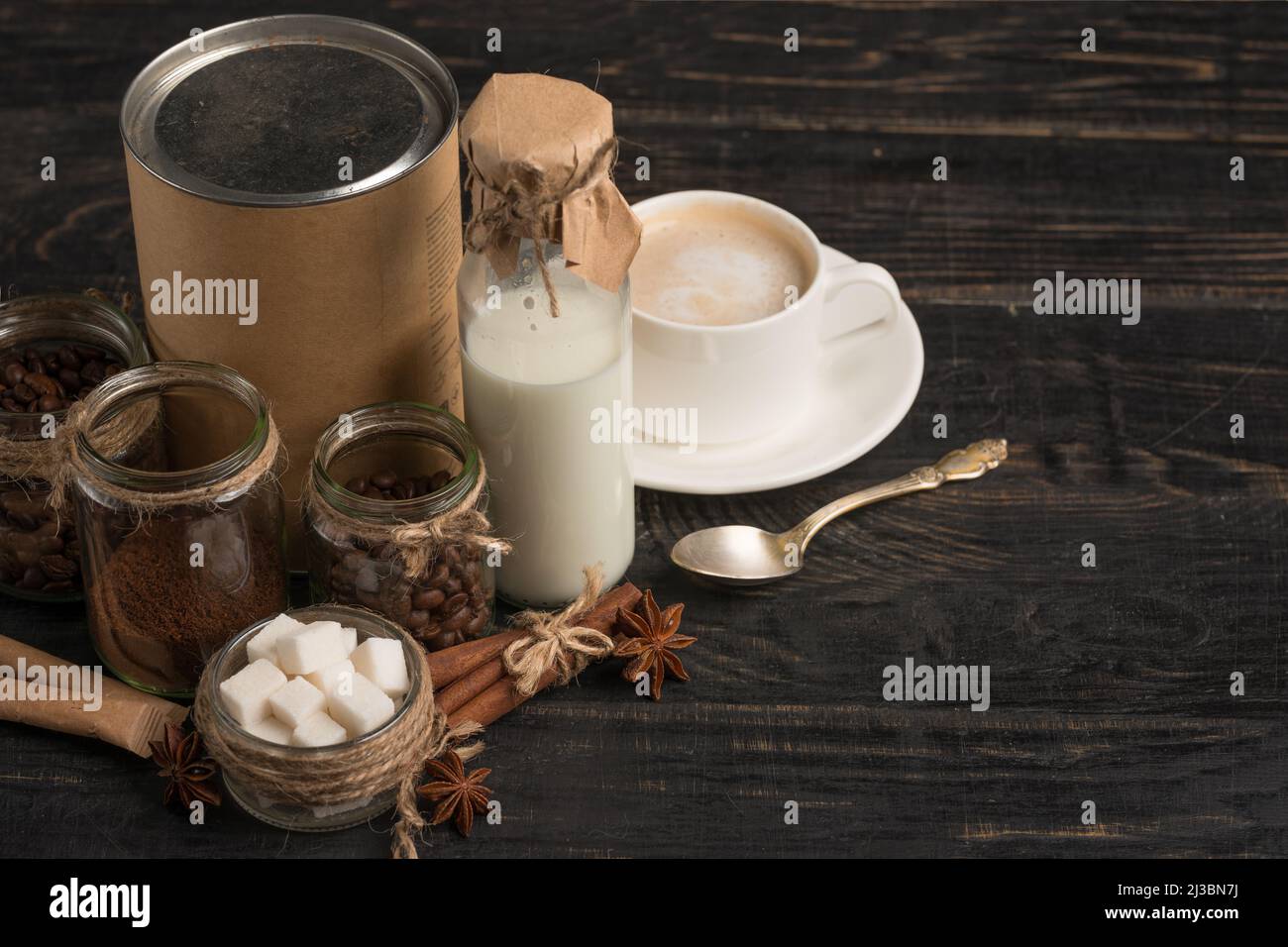 Grinded coffee, coffee beans, sugar, milk on a dark background with ...