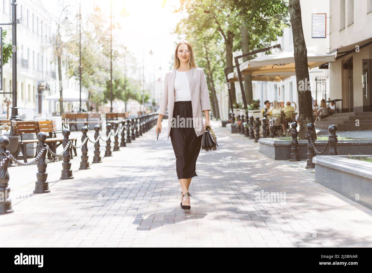 casual young woman walking along a city street Stock Photo - Alamy