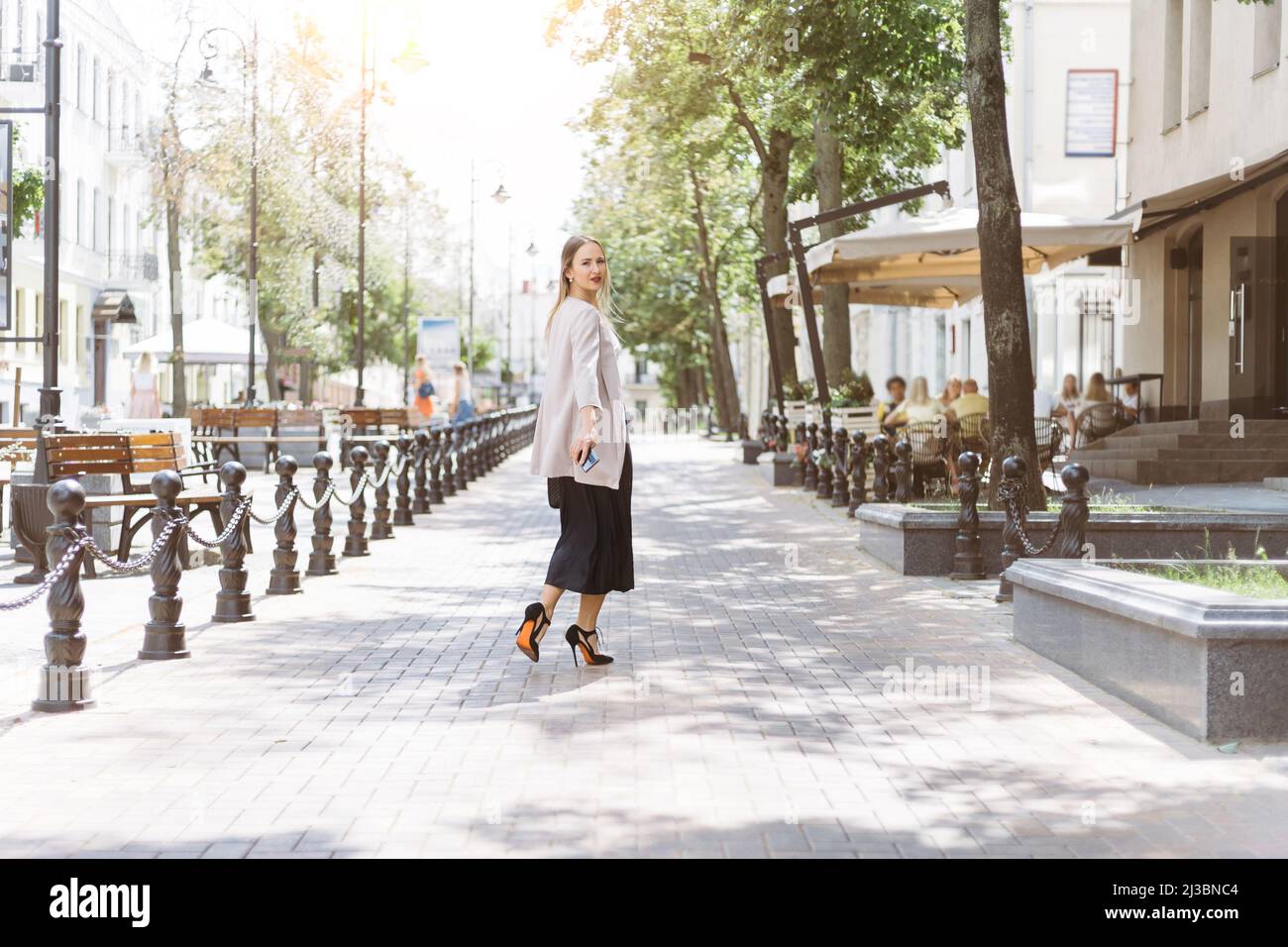 casual young woman walking along a city street Stock Photo - Alamy